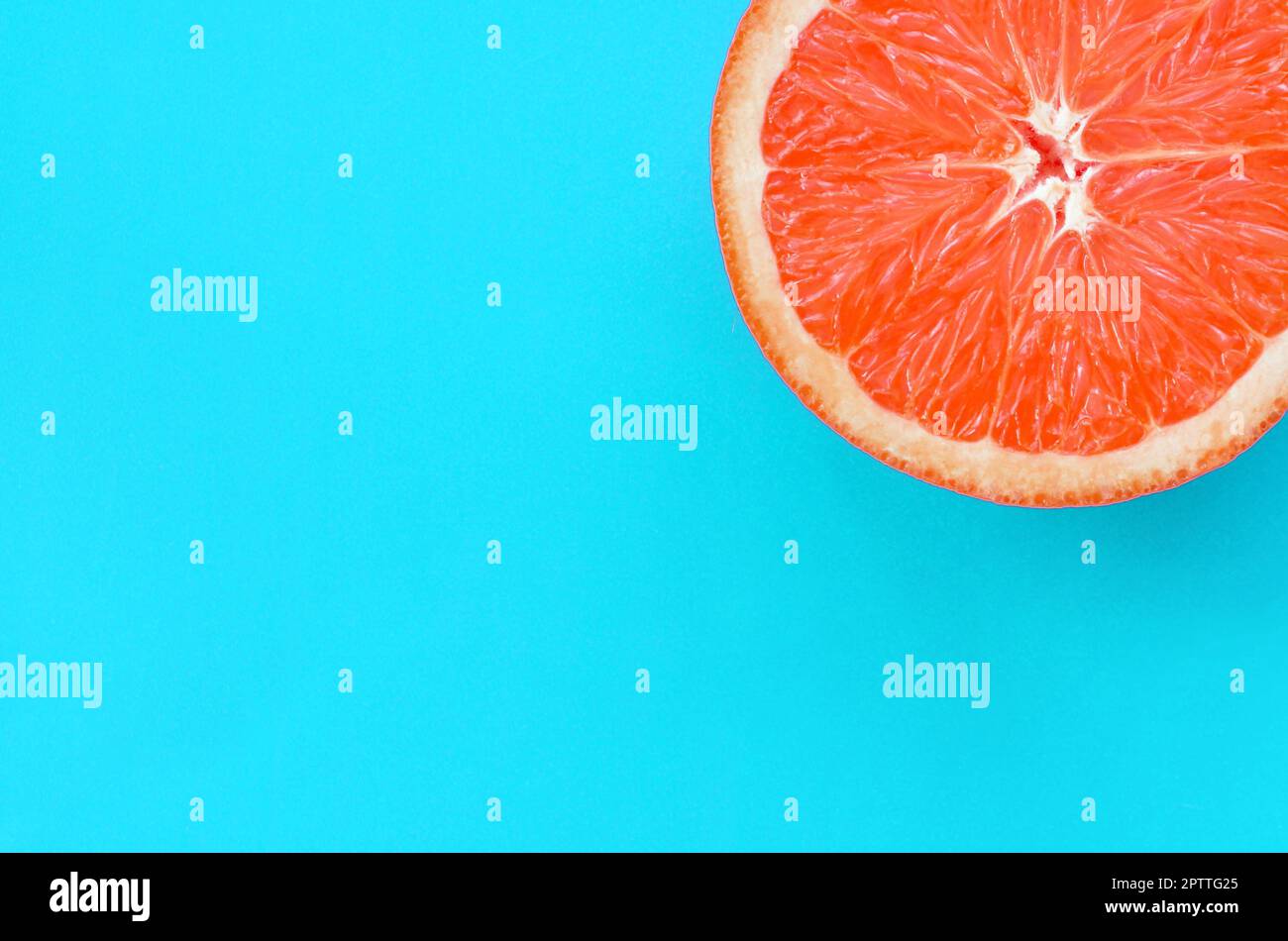 Top view of an one grapefruit slice on bright background in blue color ...