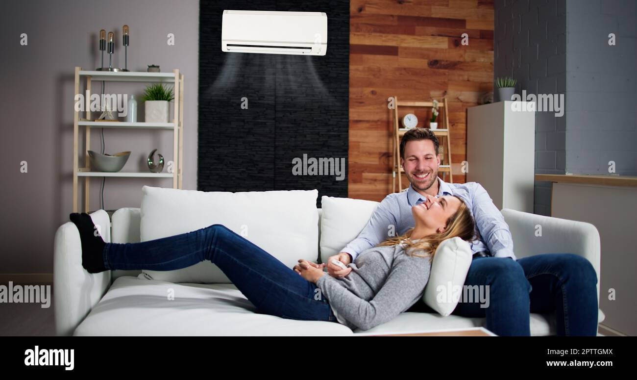 Happy Family Couple Using Air Conditioner. Apartment AC Stock Photo - Alamy