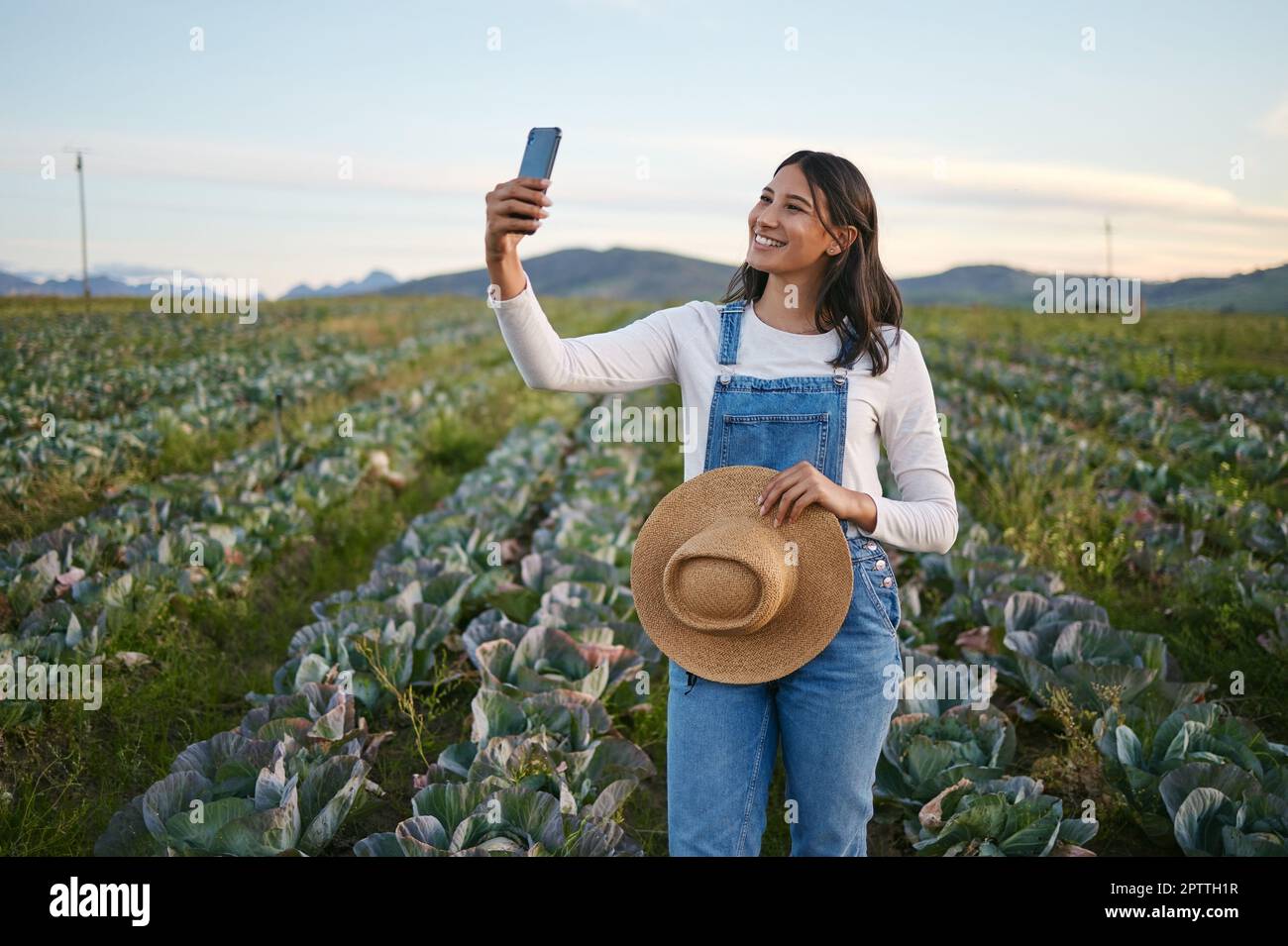 Woman farmer taking a selfie on her smartphone while standing in a ...