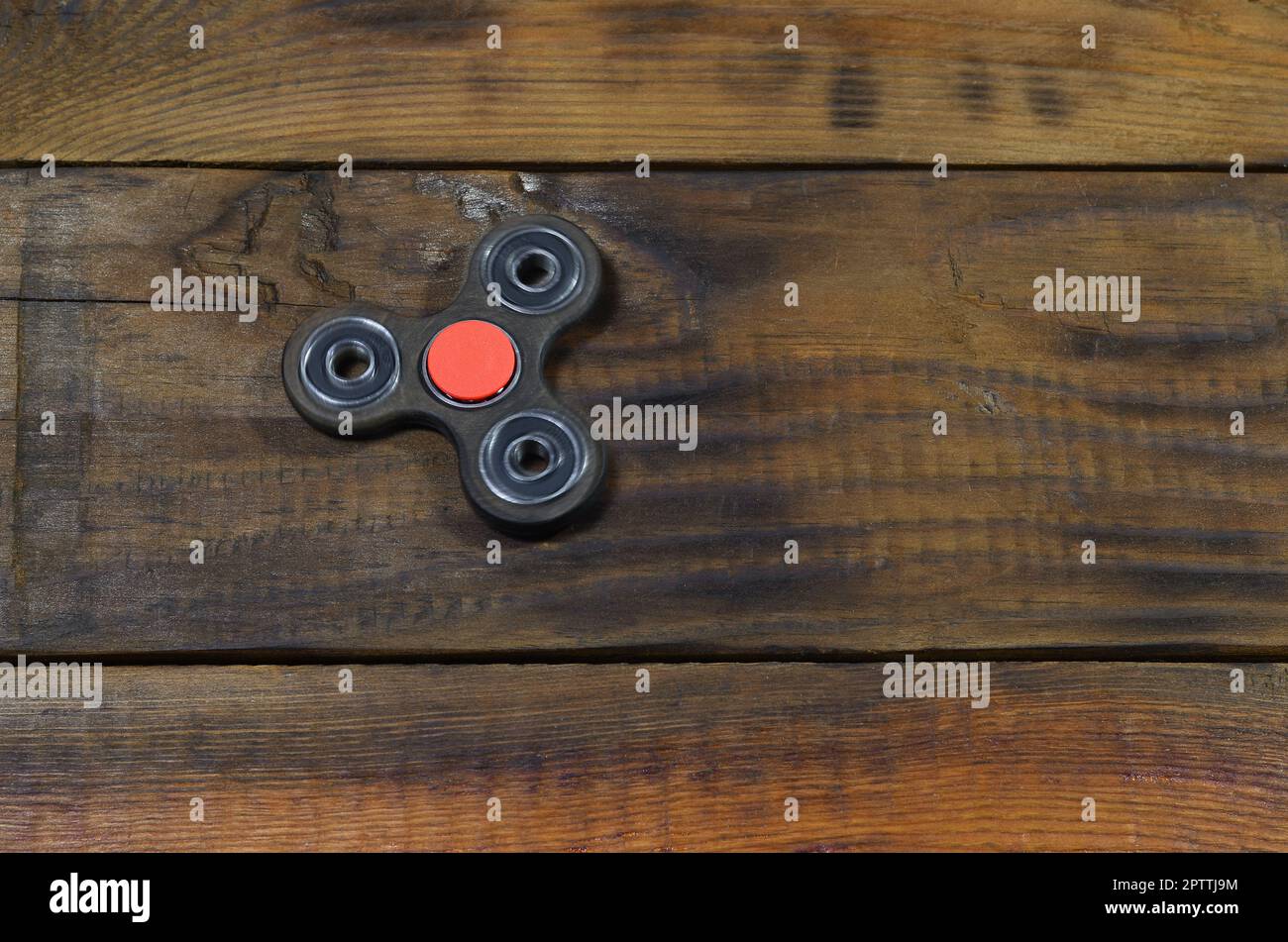 A rare handmade wooden fidget spinner lies on a brown wooden background ...