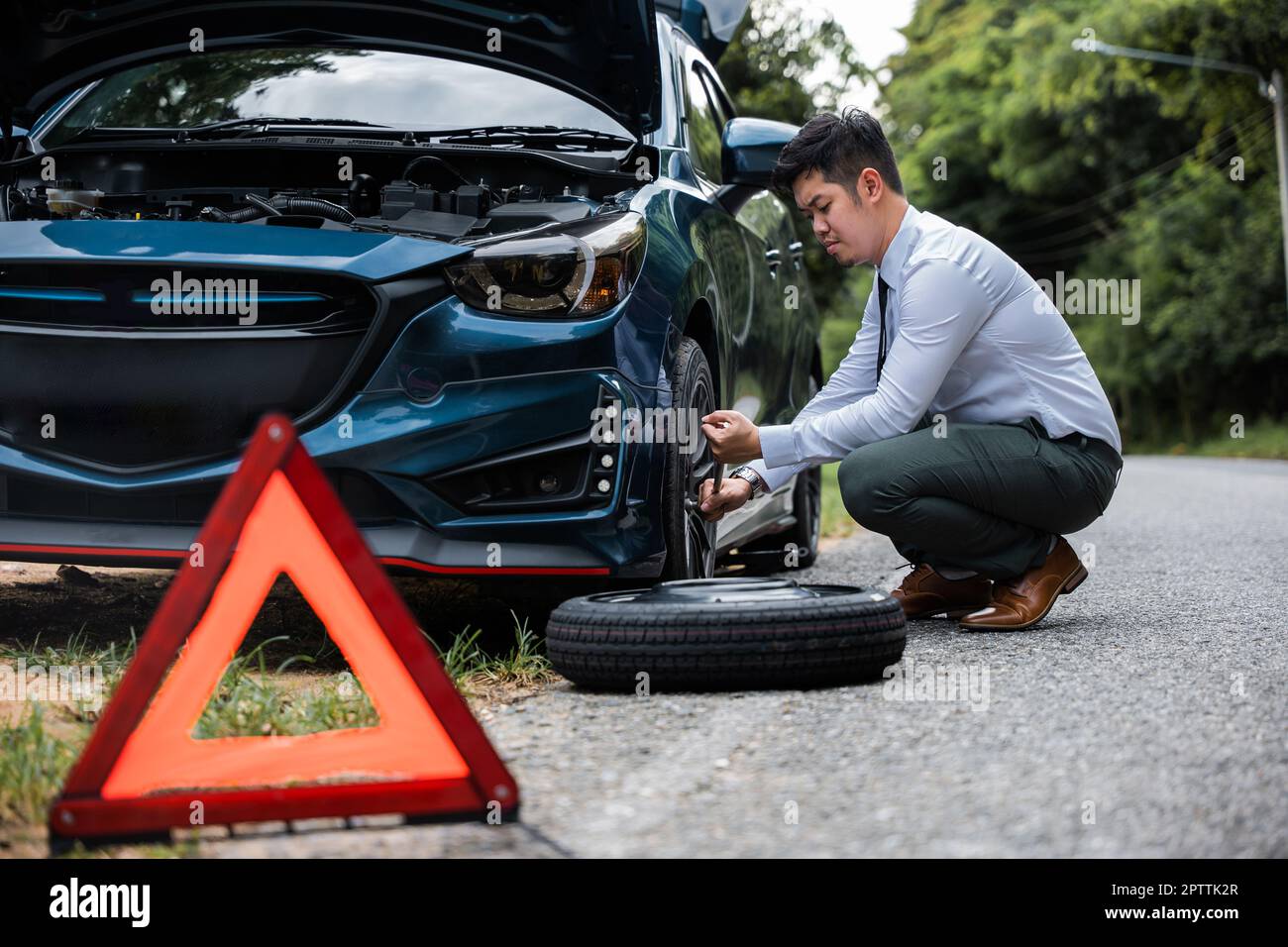 Asian businessman car broken has problems with wheel of his car during go to work in morning he ...