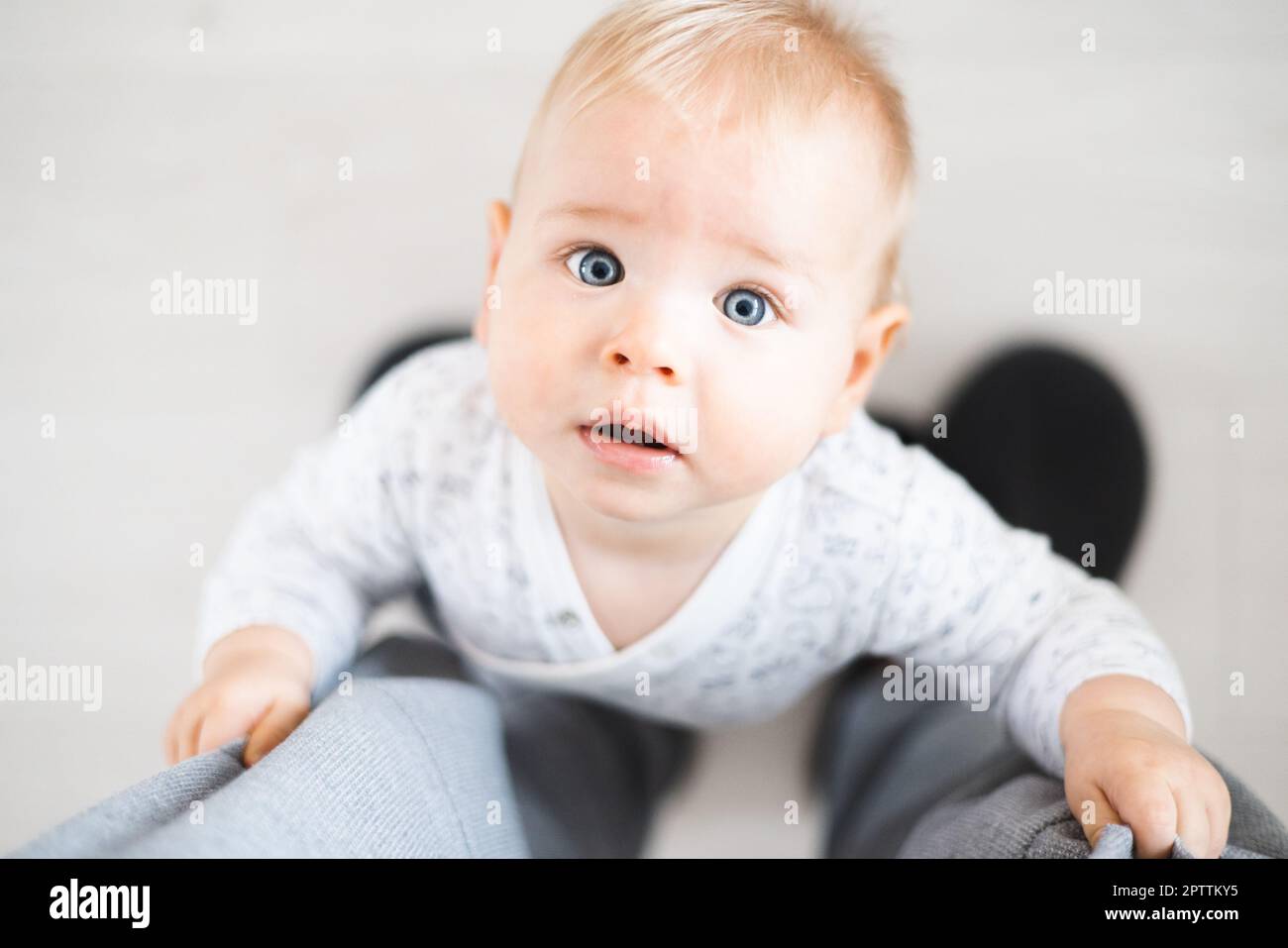 top down view of cheerful baby boy infant taking first steps holding to ...