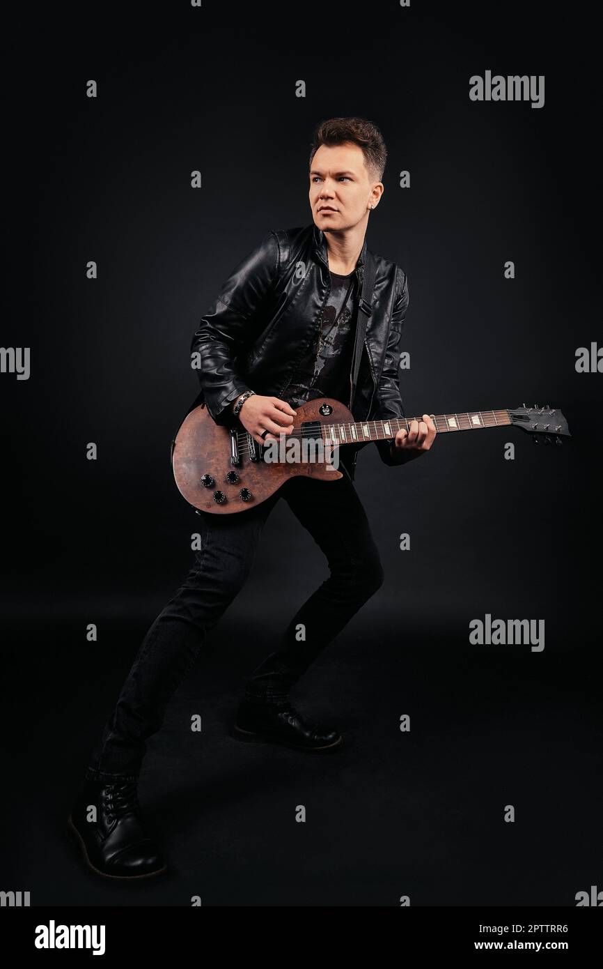 Brutal rocker playing electro guitar and dancing Stock Photo - Alamy