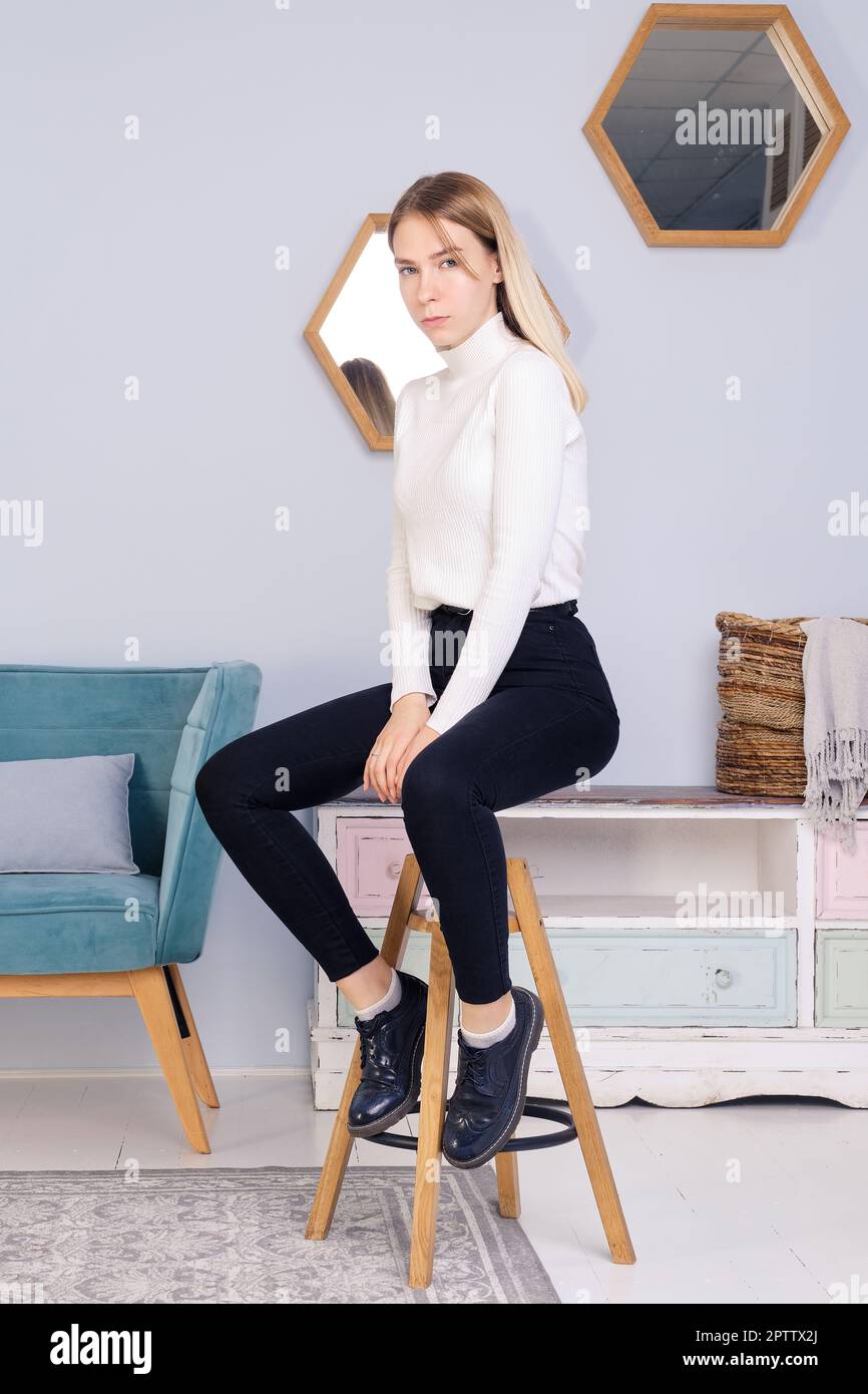 Full length portrait of young girl sitting on chair in livingroom Stock ...