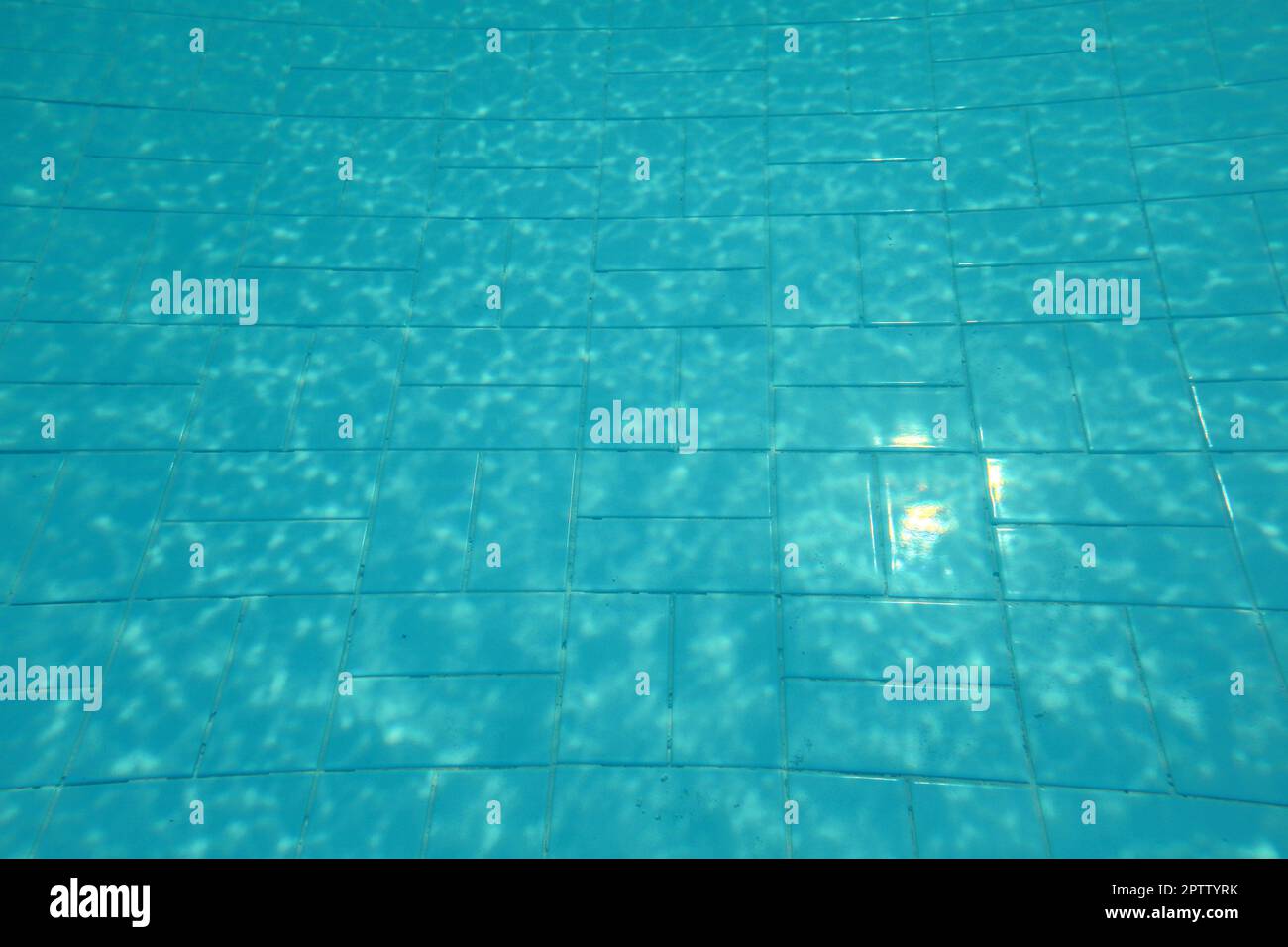 Swimming pool bottom, sun shining on blue tiles, lines distorted by ...
