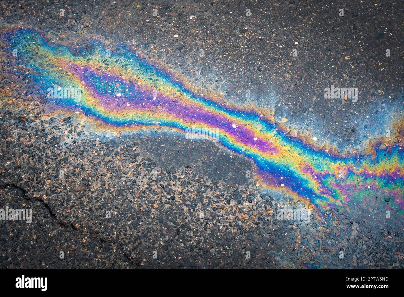 Water with patches of gasoline and oil. Spilled oil on the asphalt road ...
