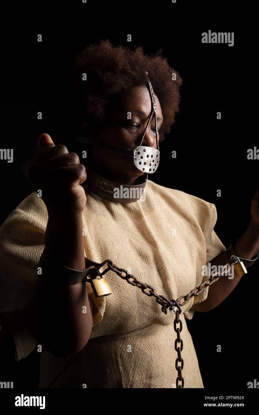 Portrait of a black woman wearing an iron mask on her face to represent ...