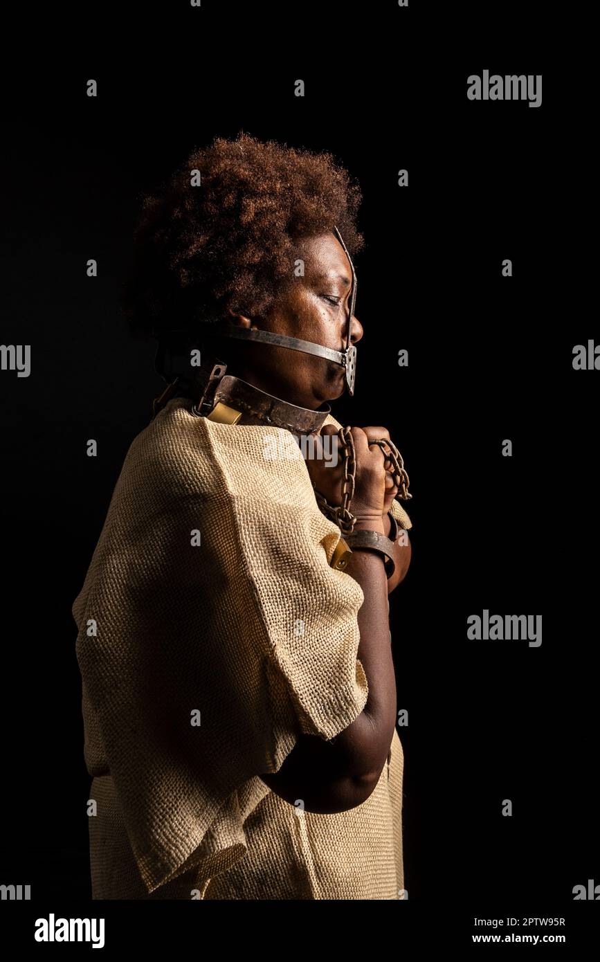 Portrait of a black woman with chains on her hands and an iron mask on ...