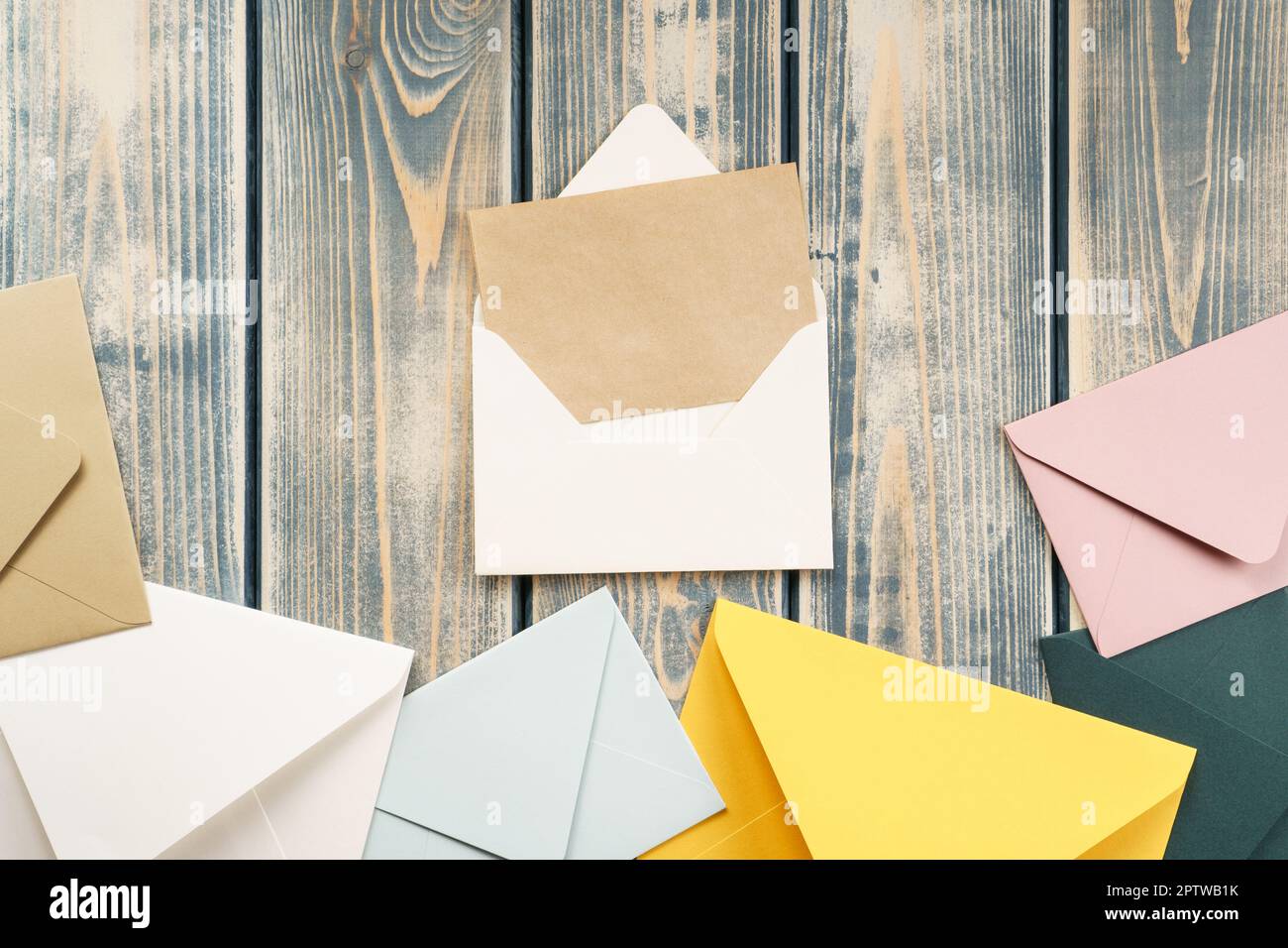 White open envelope with open kraft paper card on gray wooden ...