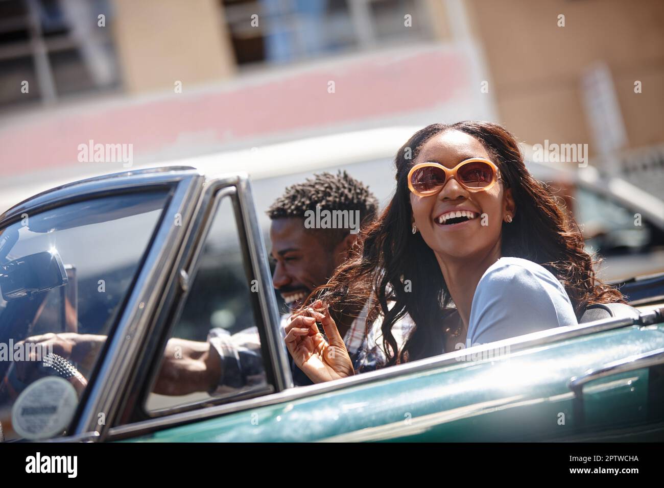 Take the long way home. A happy young couple driving in a convertible ...