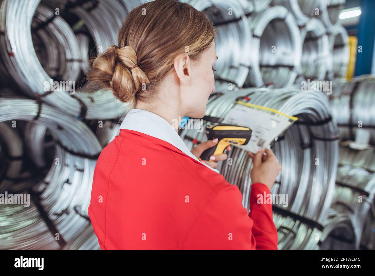 Auditor woman taking stock of metal and other materials in warehouse ...
