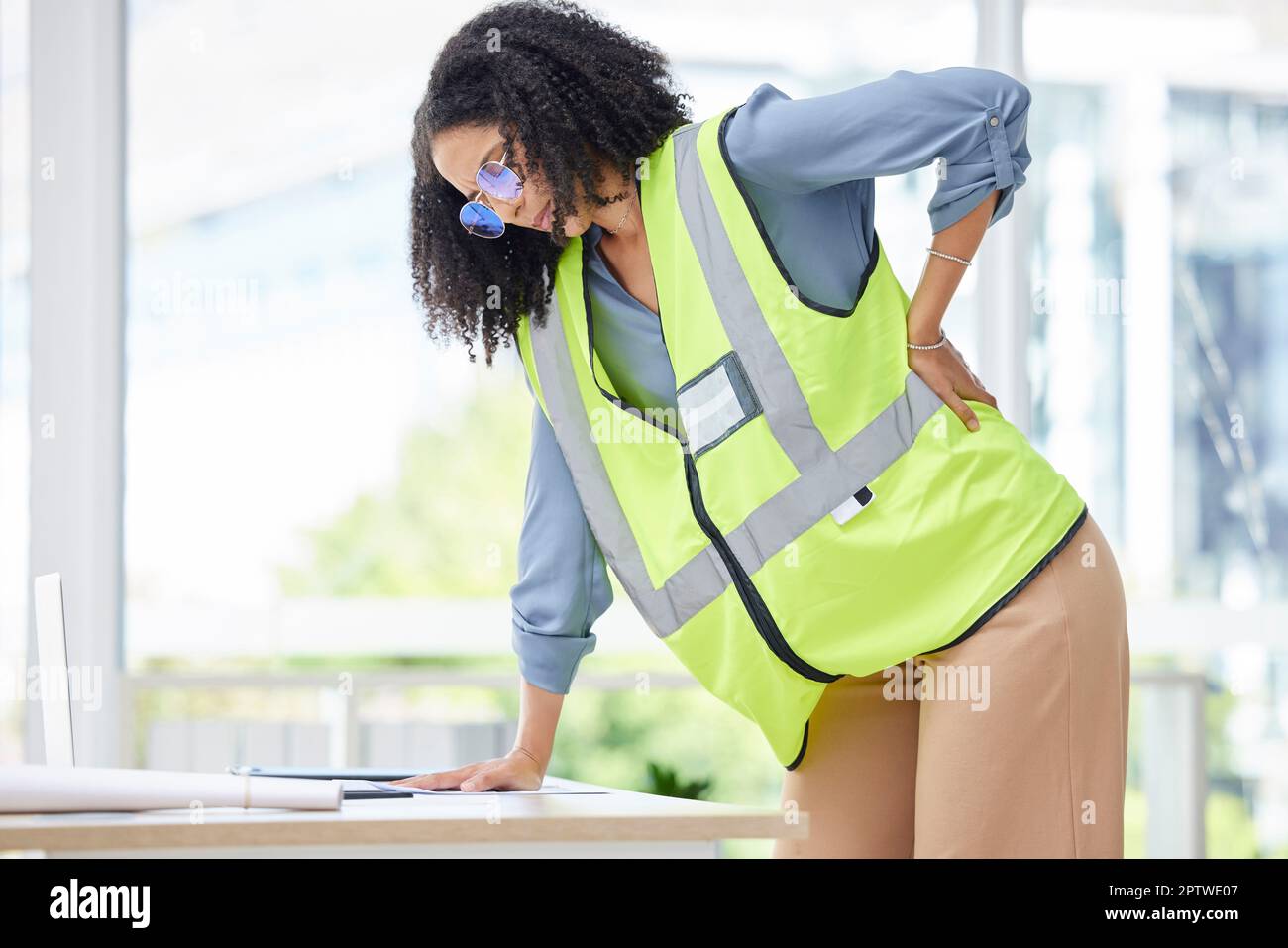 Woman, back pain and construction worker with safety vest, office or ...