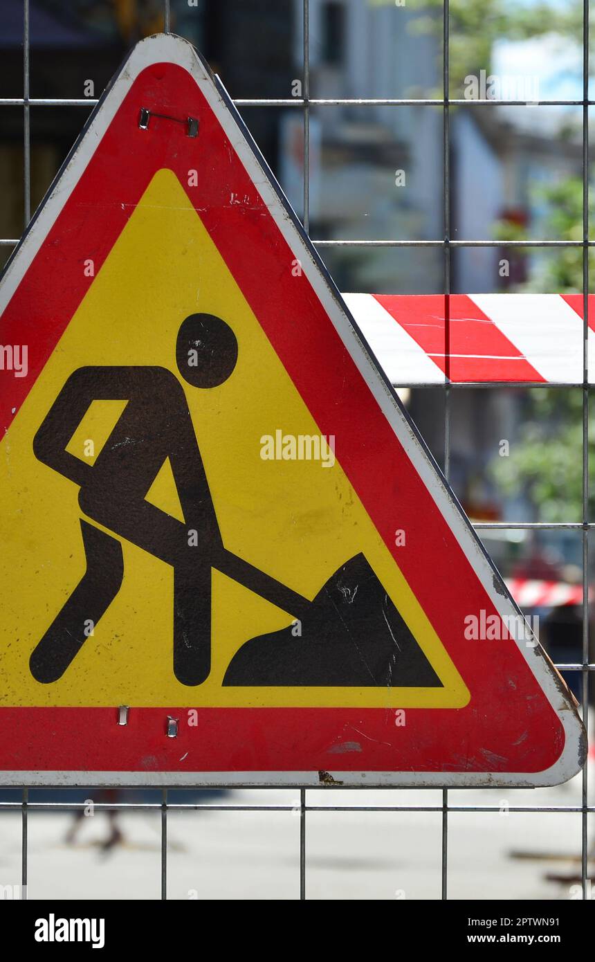 The warning sign "under construction" is attached to a metal mesh fence ...