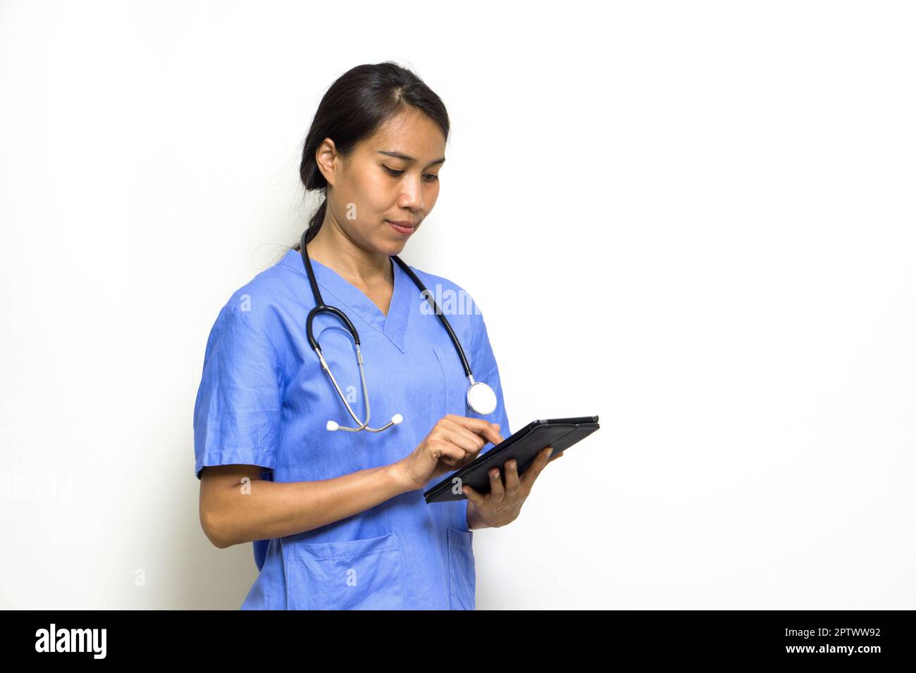 Woman physical therapist in blue uniform and stethoscope typing on ...