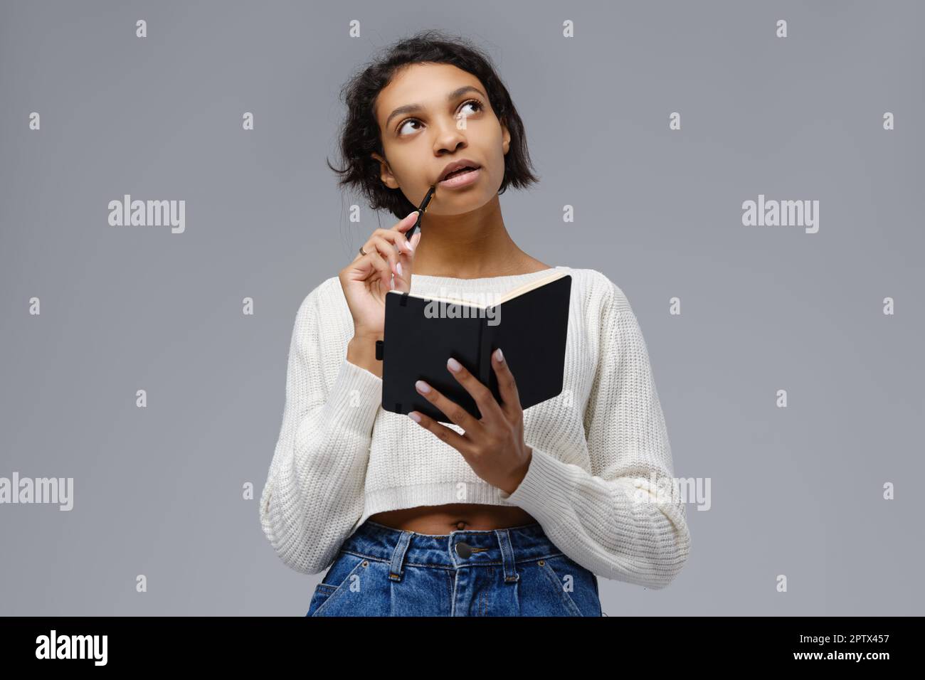 Young african woman recalls past events to write in a diary, looks up ...