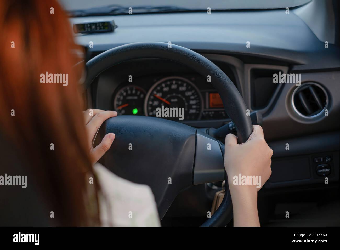 A young female sits in the driver's seat and has her hands on the ...