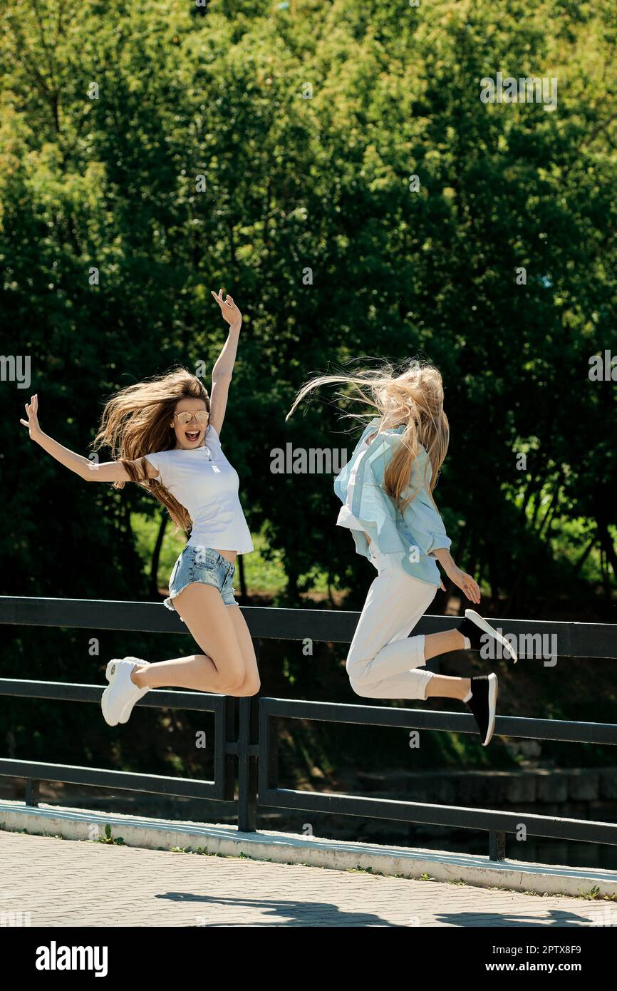 Two positife and funny girls jumping together Stock Photo - Alamy