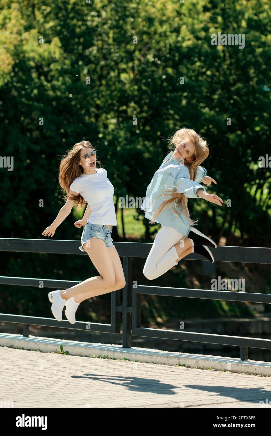 Two positife and funny girls jumping together Stock Photo - Alamy