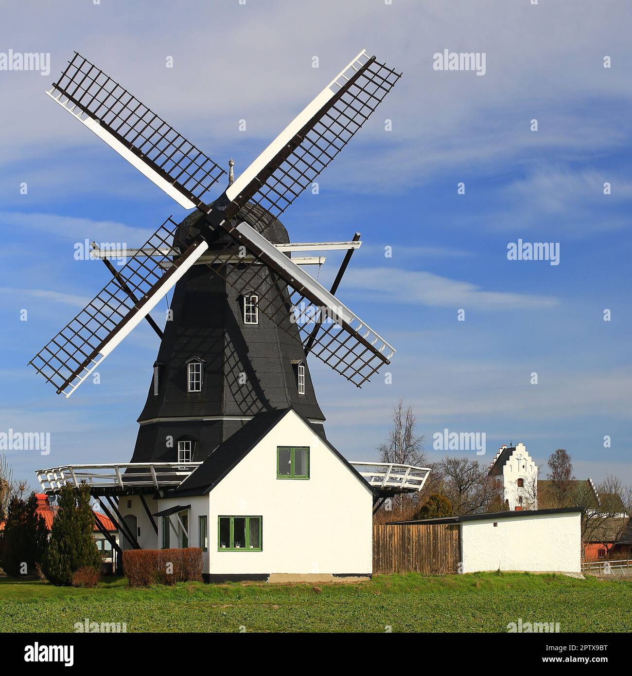 Historic smock mill with church in background in Kyrkokopinge, near ...