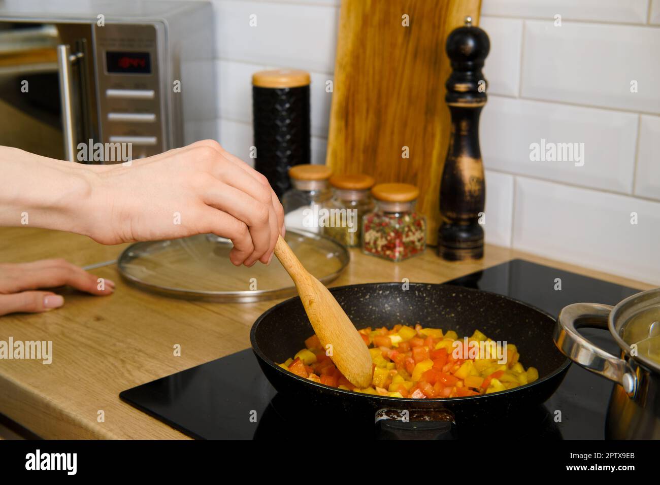 Closeup view of female hand stirring chopped vegetables in a frying pan ...