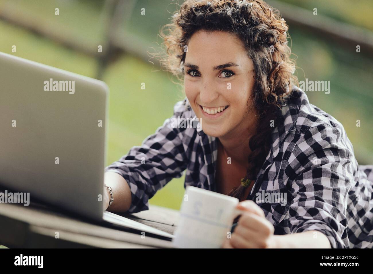 Young curly-haired woman decided to do laptop work outdoors, to avoid ...