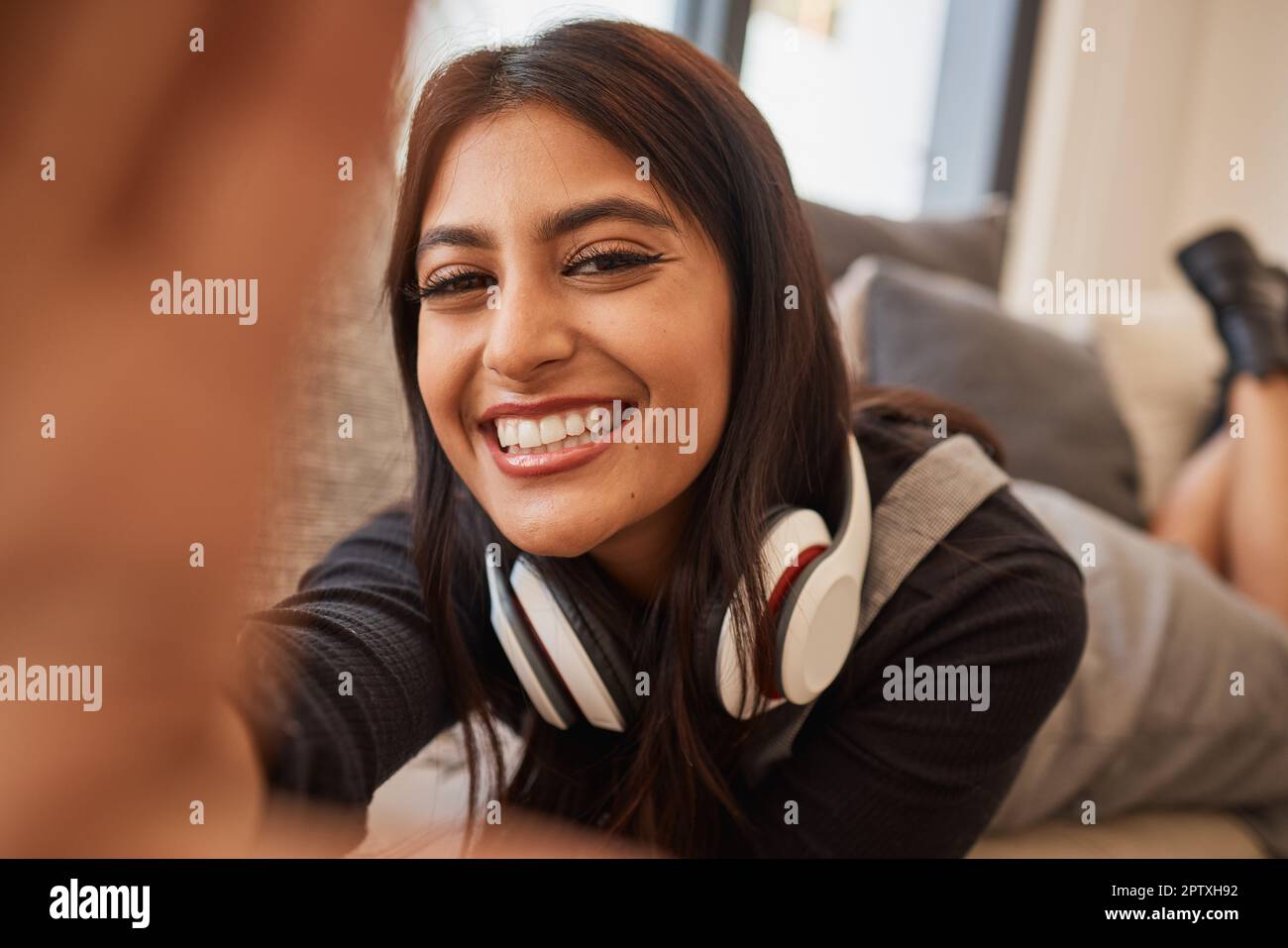 Headphones, selfie and woman relax on sofa with virtual, video call or ...