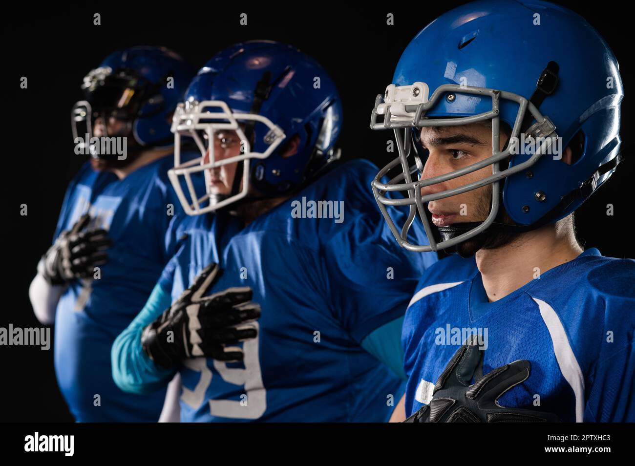 Portrait of three men in blue uniforms for American football with a ...