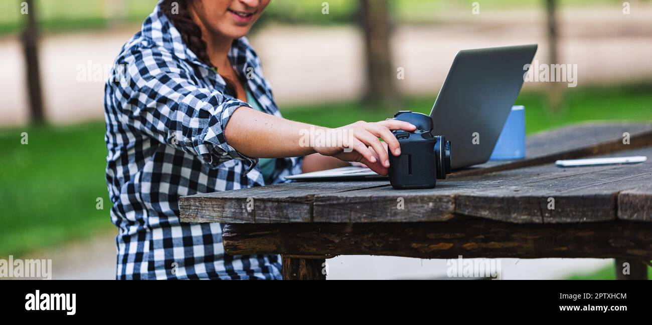 Human photographer works on her shoot in the countryside, outdoors. She ...