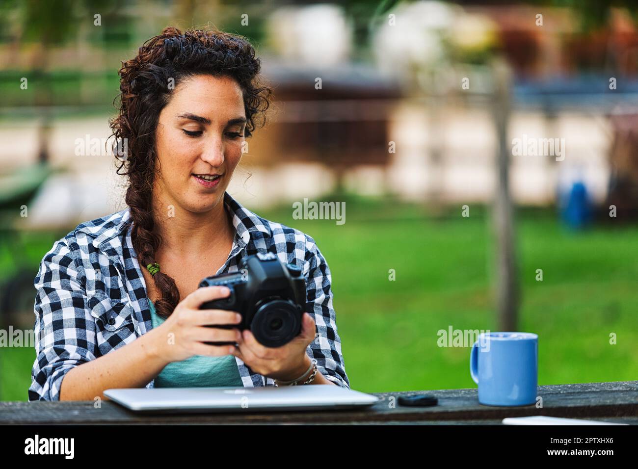 Human photographer works on her shoot in the countryside, outdoors. She ...