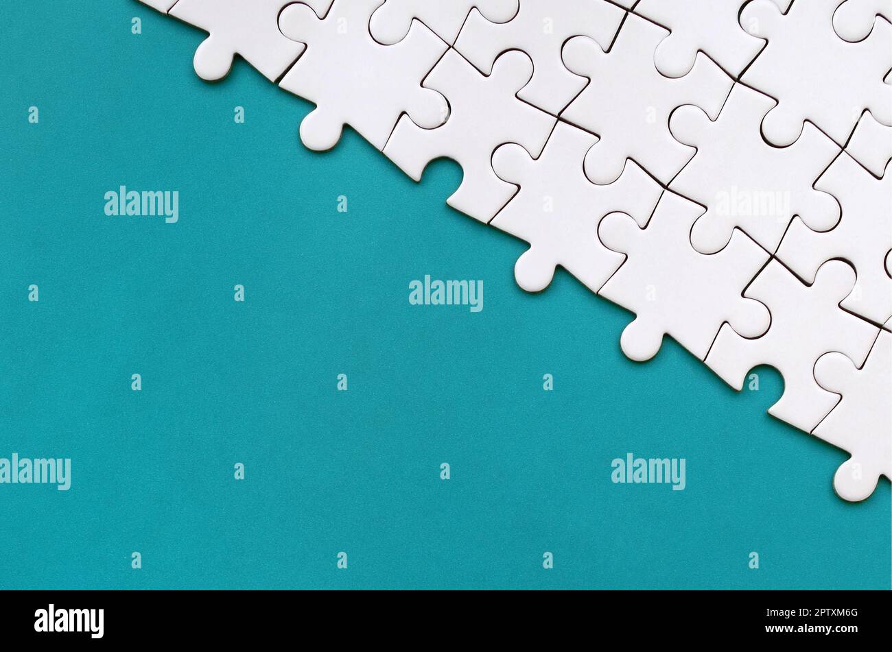 Fragment of a folded white jigsaw puzzle on the background of a blue ...