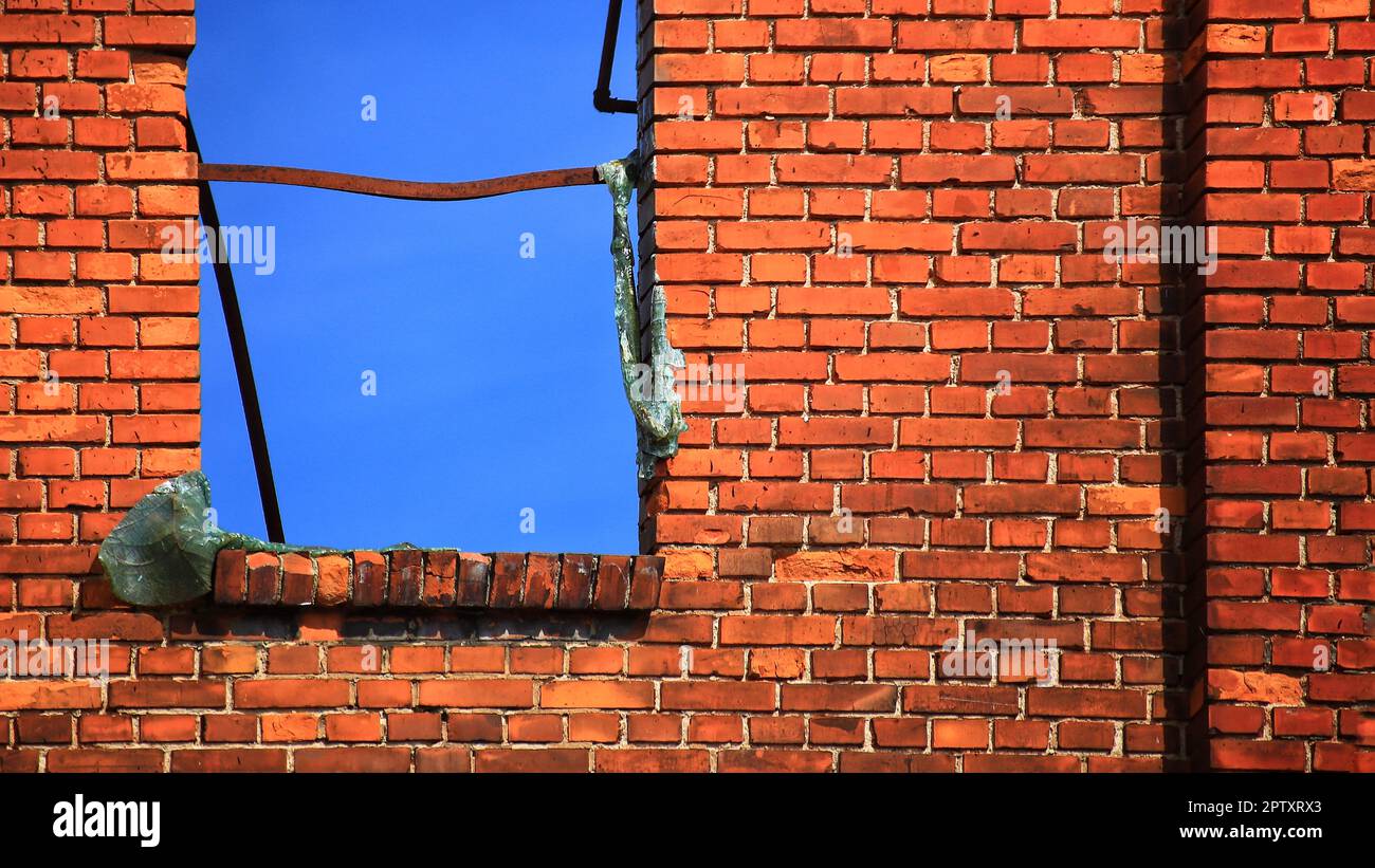 Window frame in brickwall with blue sky, the glass is molten due to a ...