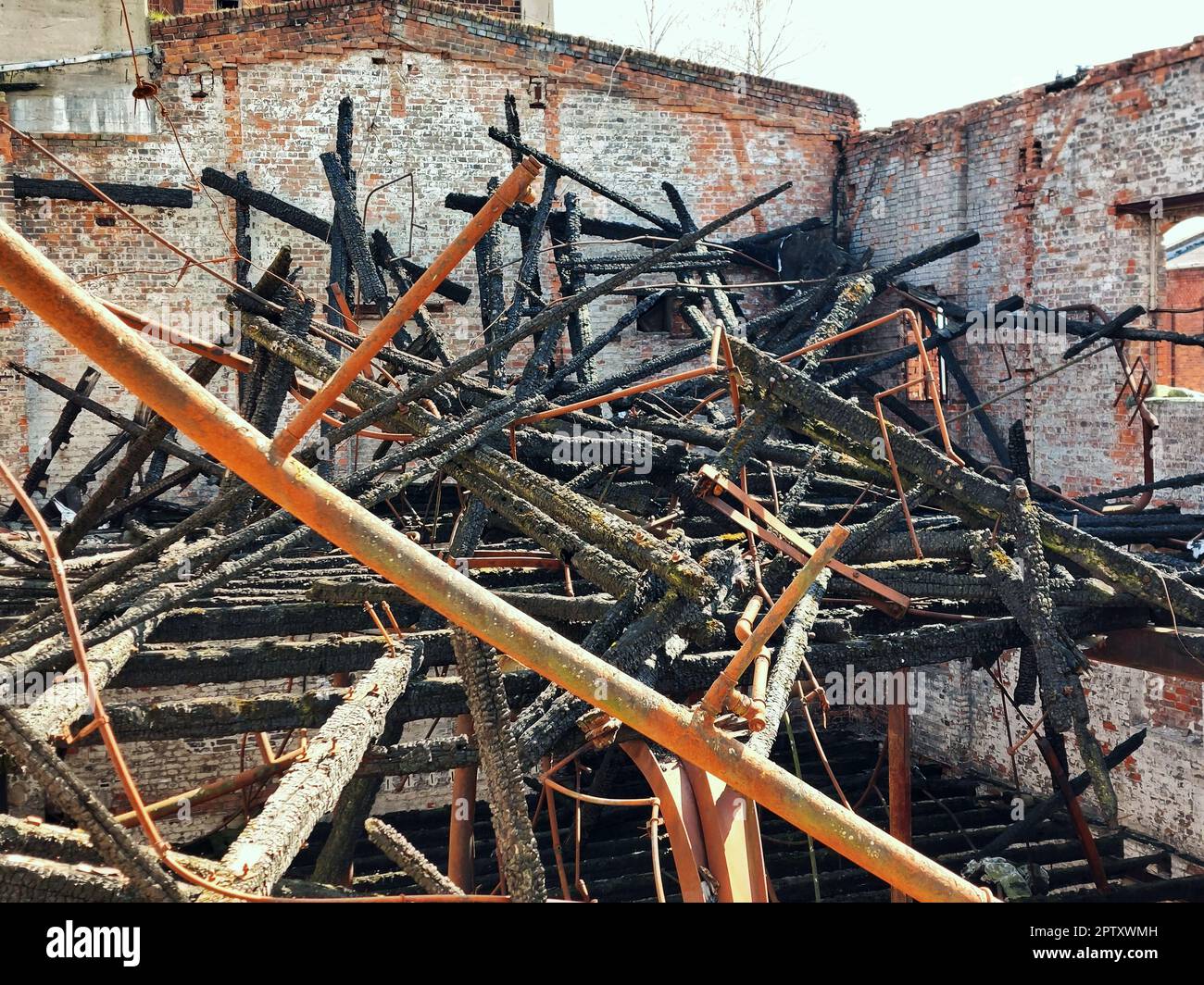 Burnt wooden beams and steel pipes on a warehouse with multiple storeys ...