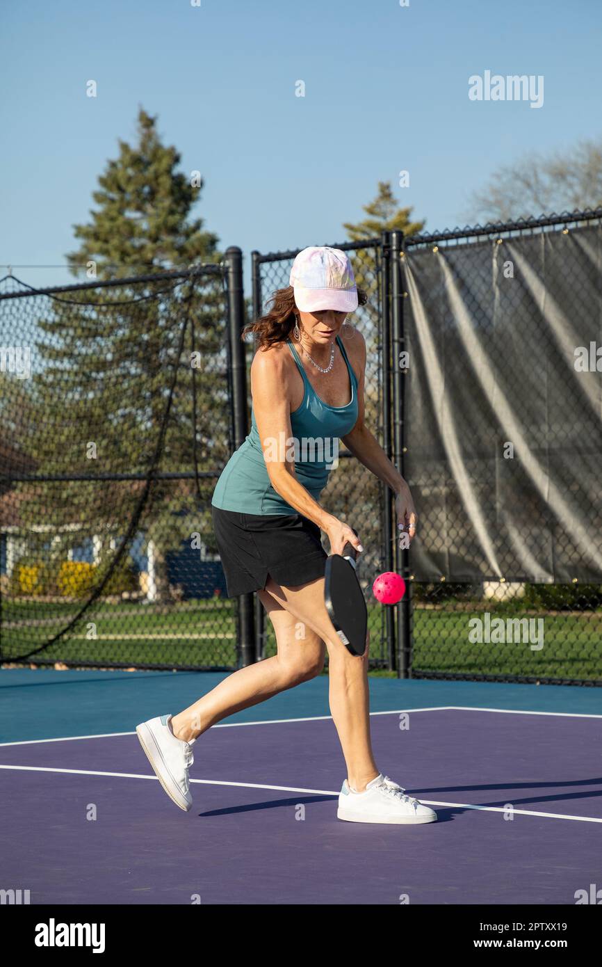 A female pickleball player returns a bright pink ball on a dedicated ...