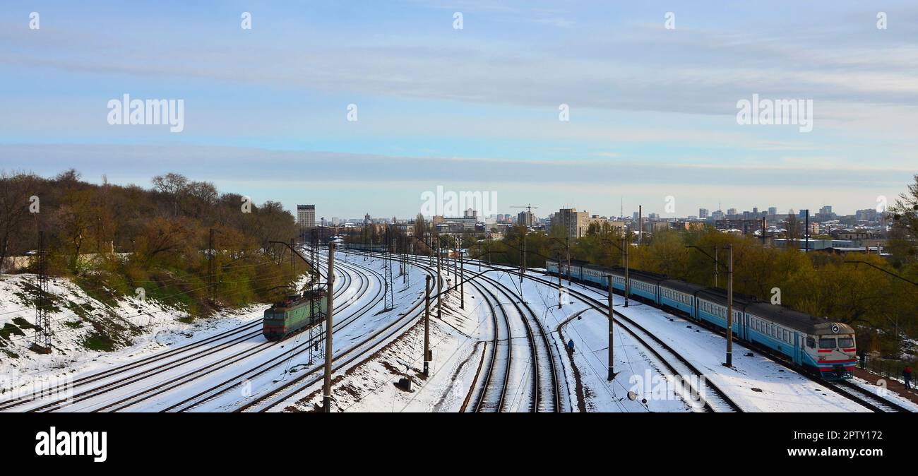 Winter landscape with a railway train on a railway surrounded by a city ...