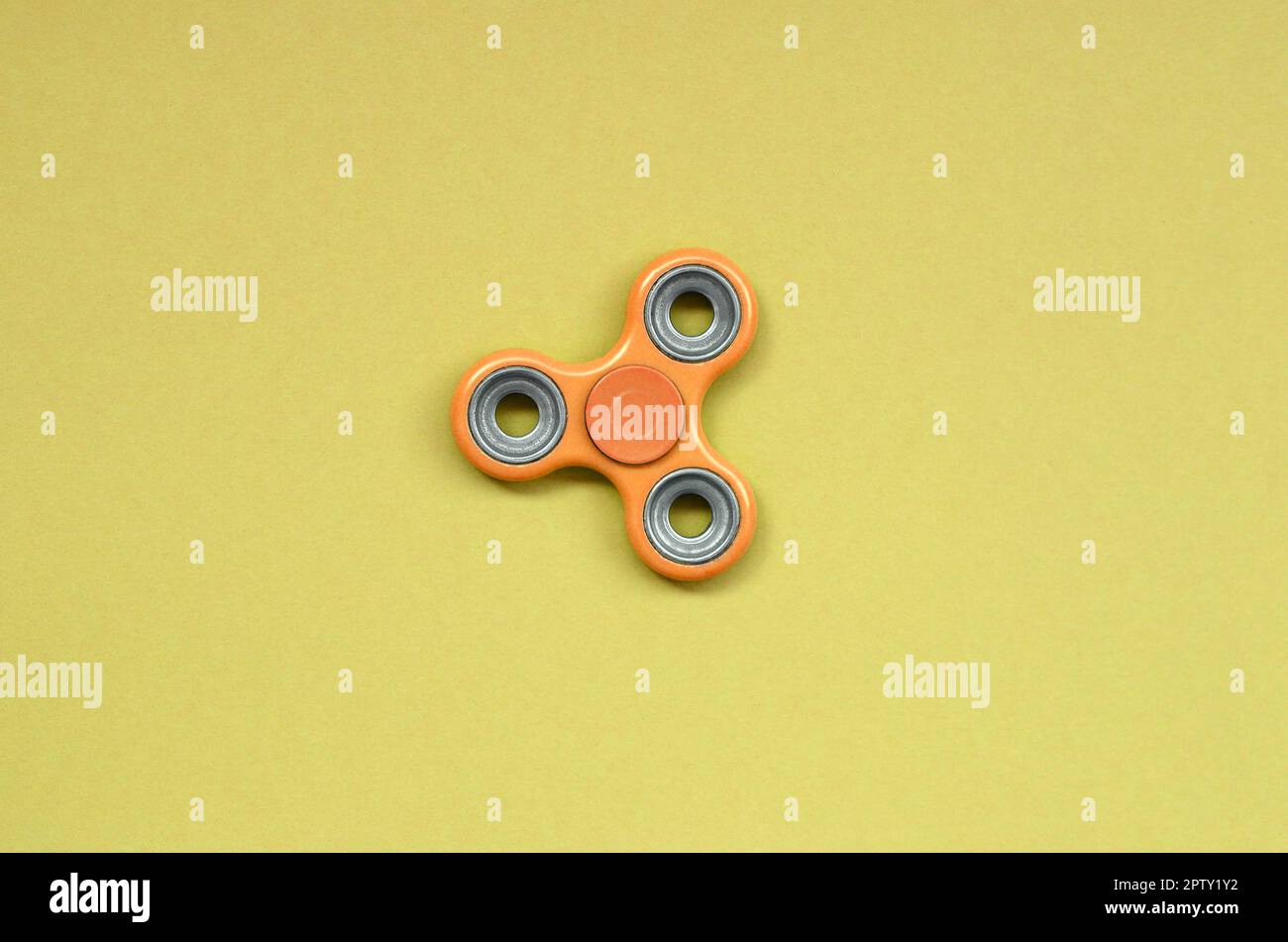 orange fidget spinner lies on texture background of fashion pastel ...