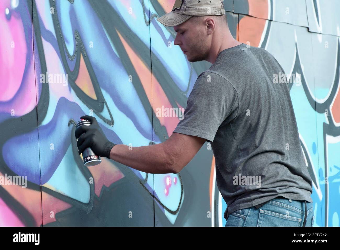 Young caucasian male graffiti artist drawing big street art painting in ...