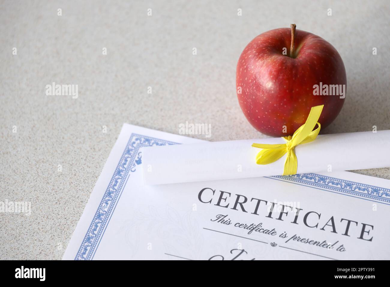 A certificate of achievement lies on table with small scroll and red ...