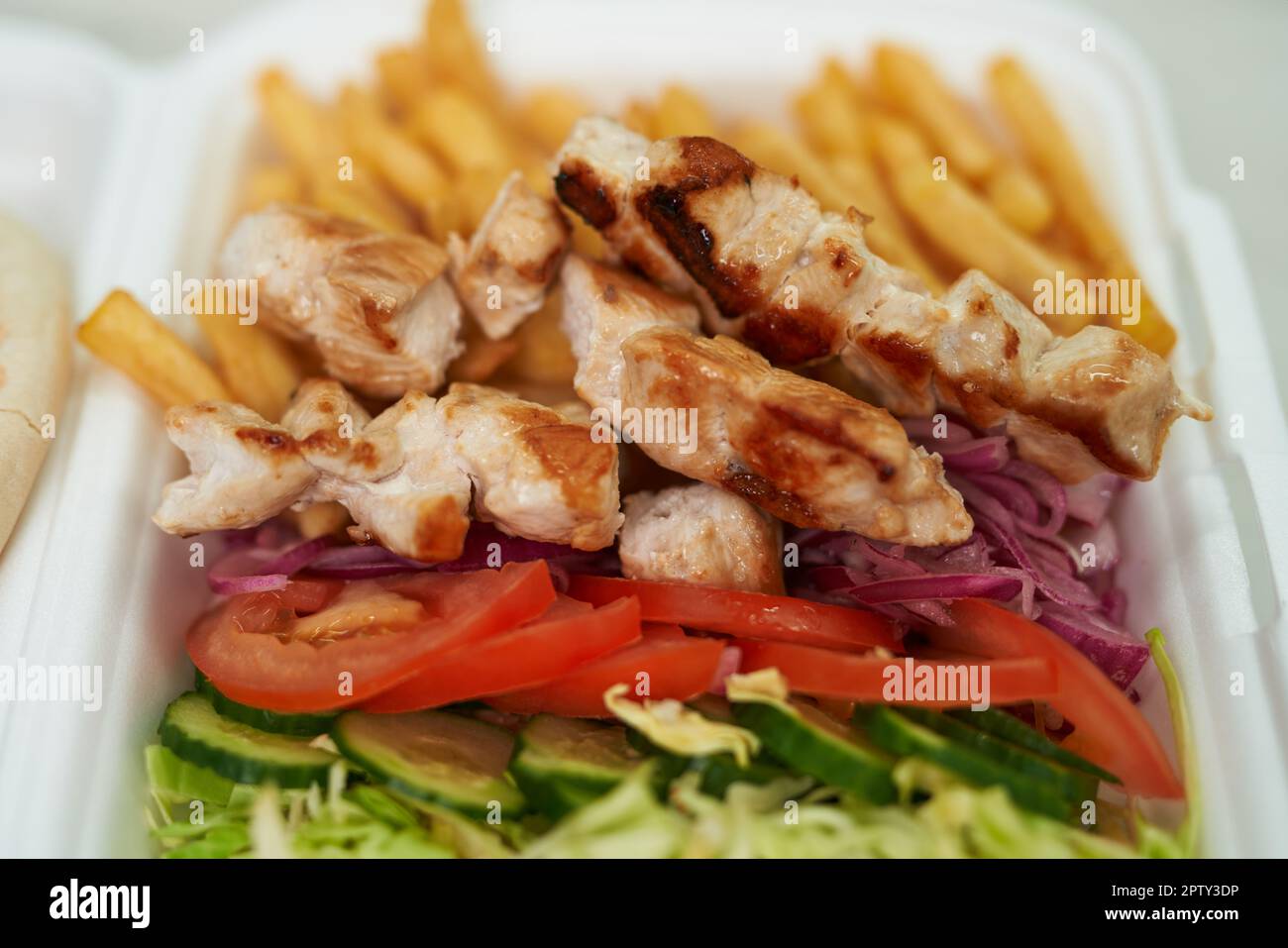 Styrofoam lunch box with Greek kalamaki dish. Traditional souvlaki meat ...