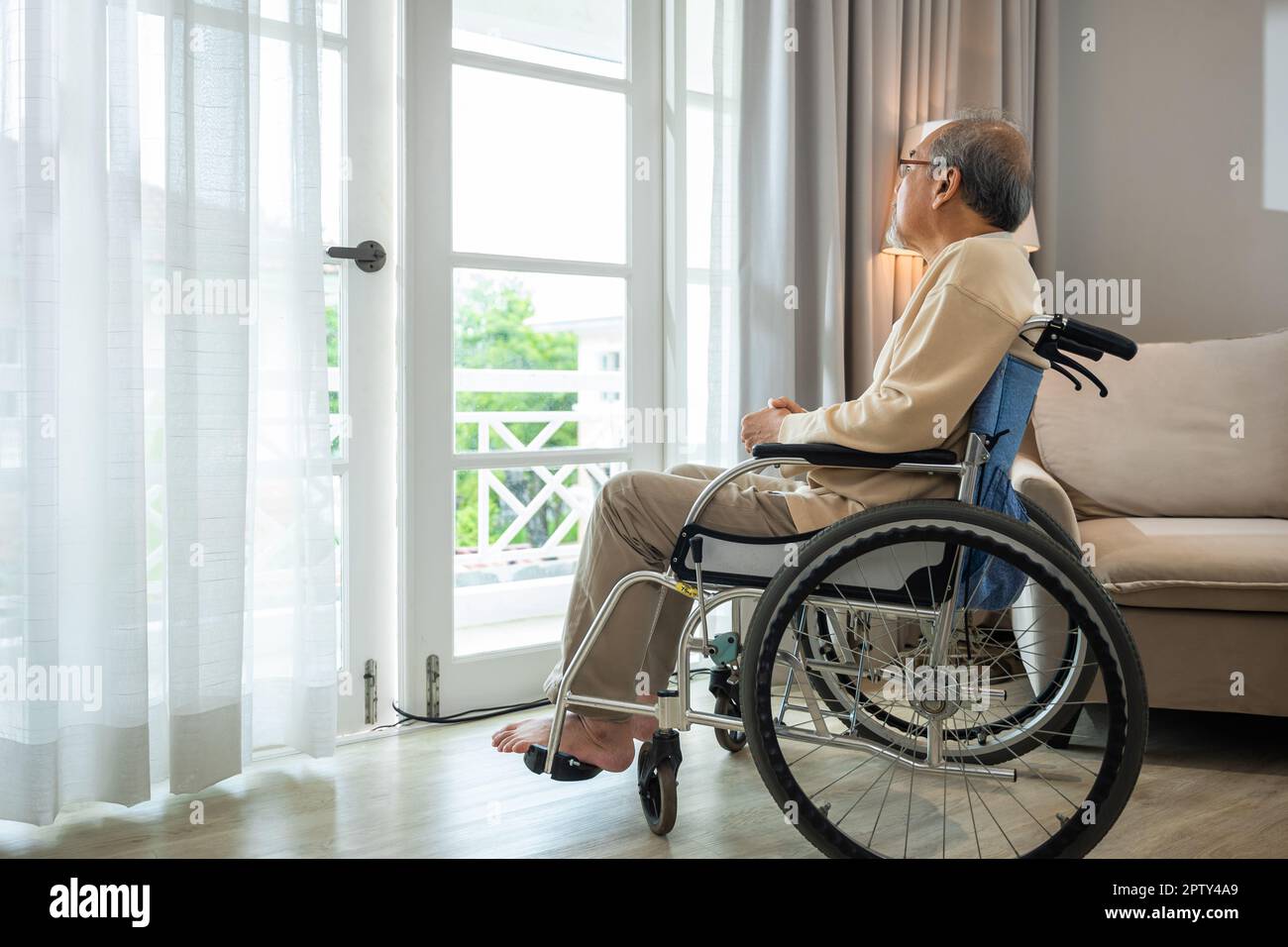 Asian senior man disabled sitting alone in wheelchair looking through ...