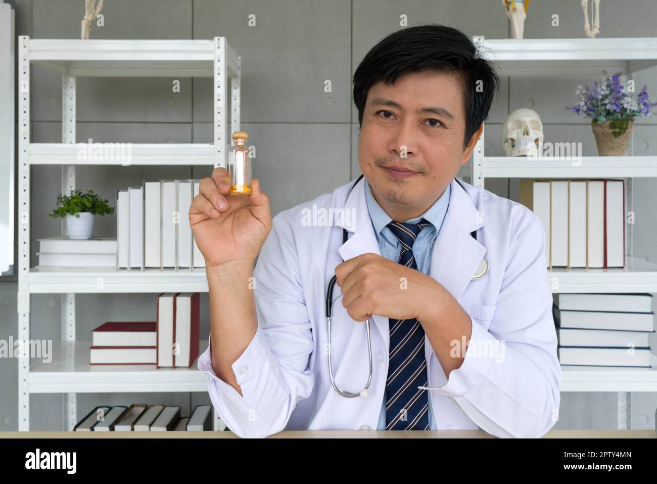 Asian doctor in white gown and stethoscope holding medical capsule ...