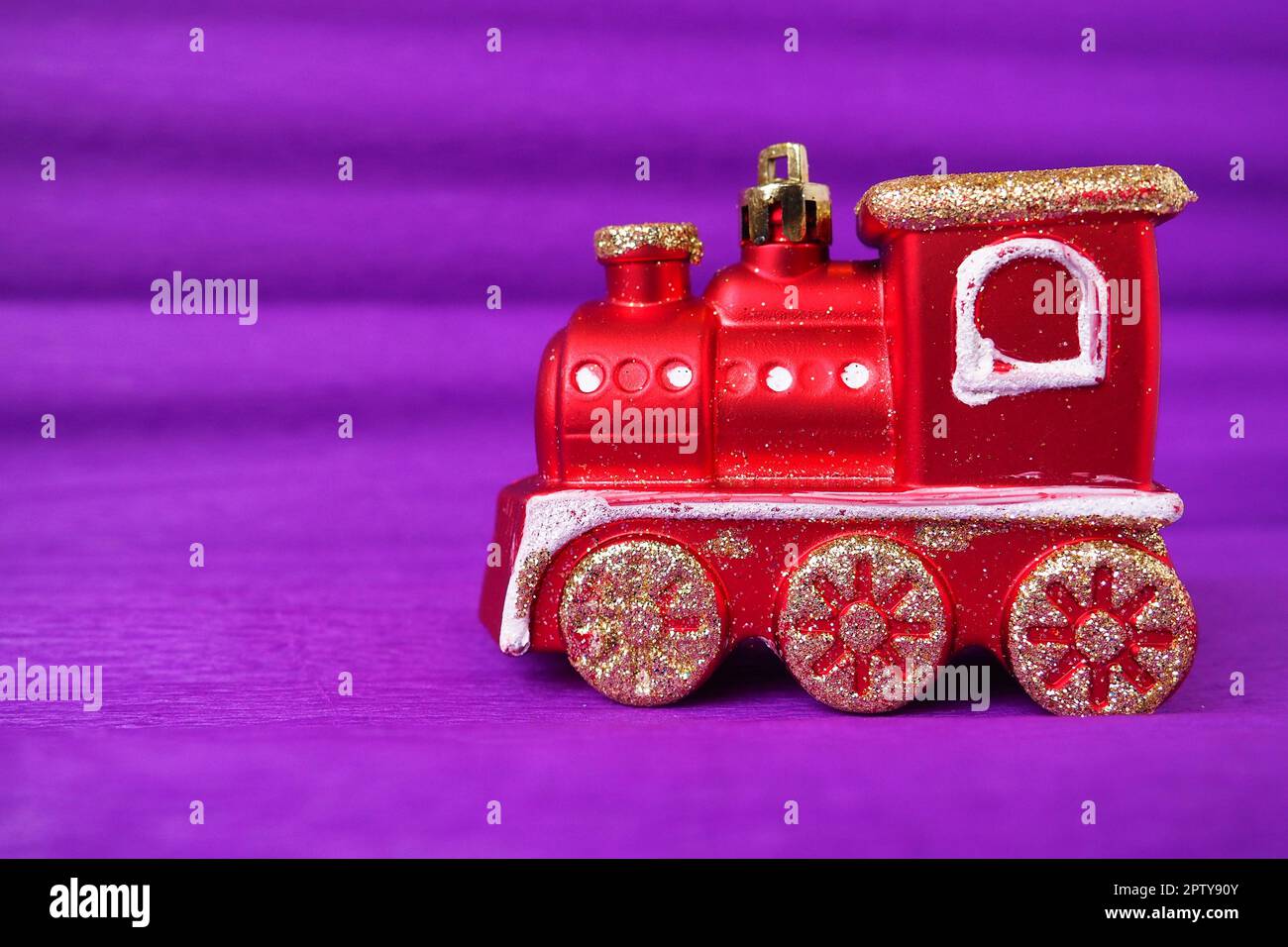 Red toy train locomotive on a purple and lilac gradient background. New ...