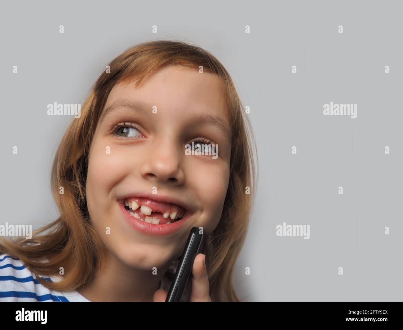 A 7-year-old girl without a front tooth. The child smiles, looks to the ...