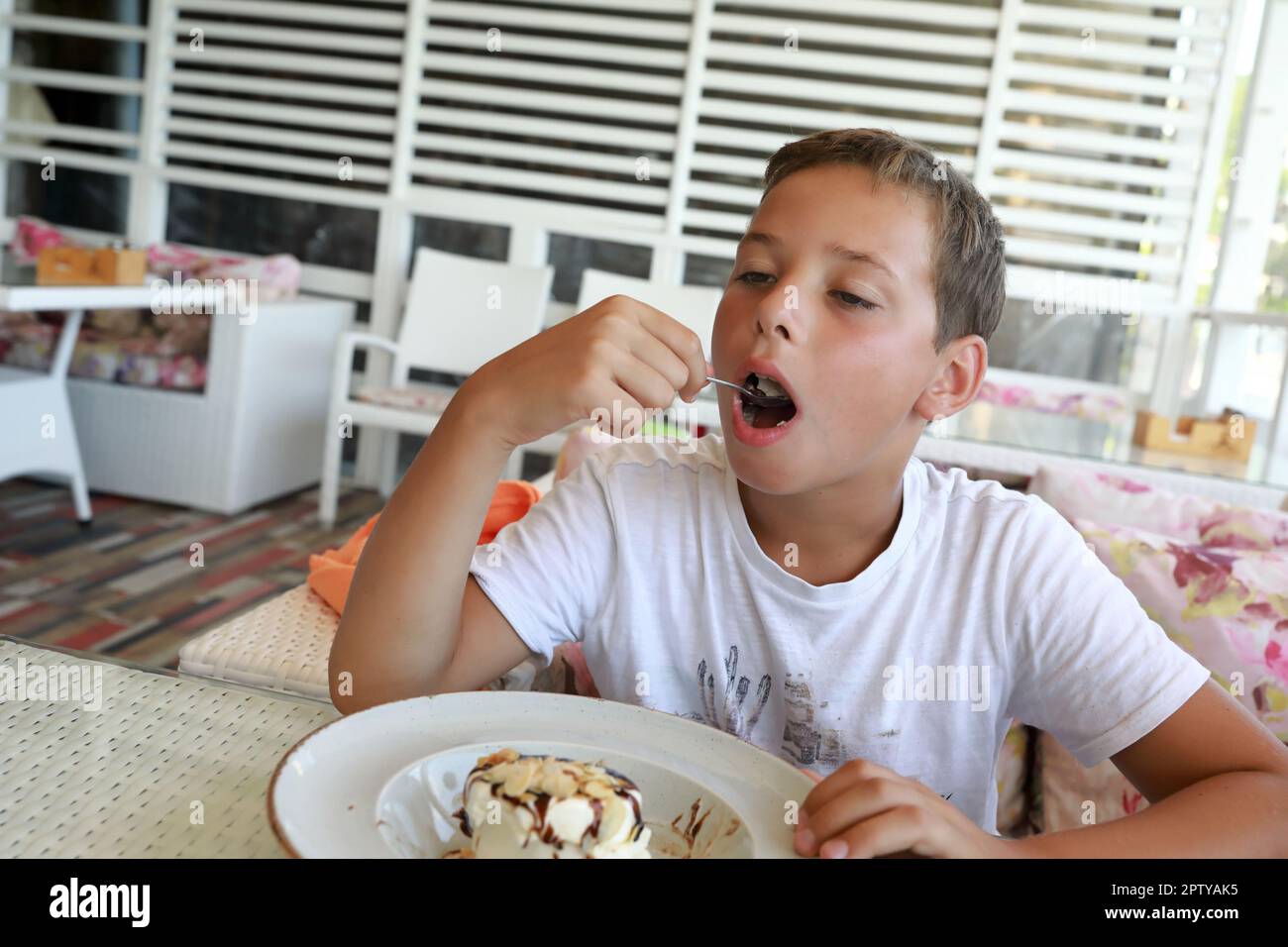 Boy eating vanilla ice cream in restaurant Stock Photo - Alamy