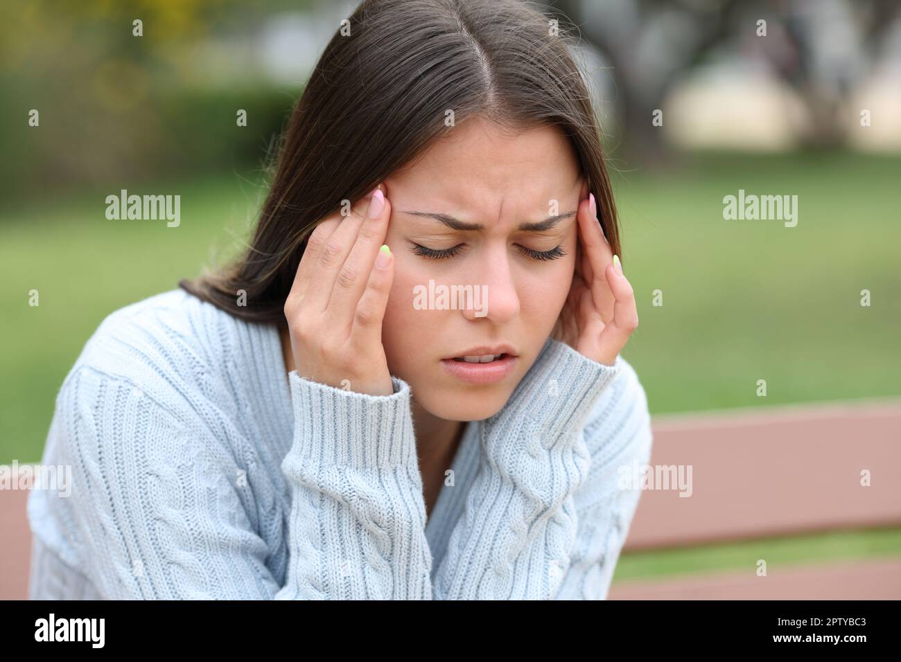 Teen suffering headache complaining sitting in a park Stock Photo - Alamy