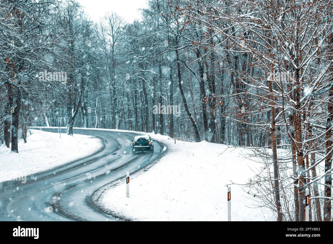 Car passing on a road with snow slush and snow fall, winter scenery ...