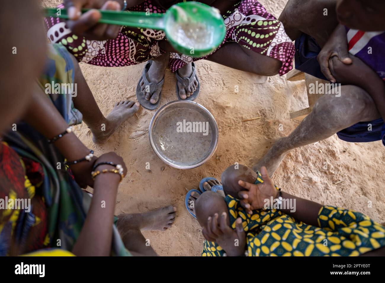 Four children in an IDP settlement share a small bowl of millet ...