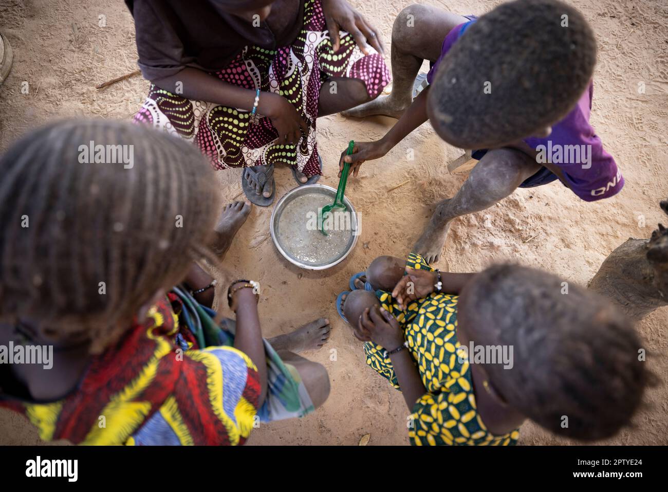 Four children in an IDP settlement share a small bowl of millet ...