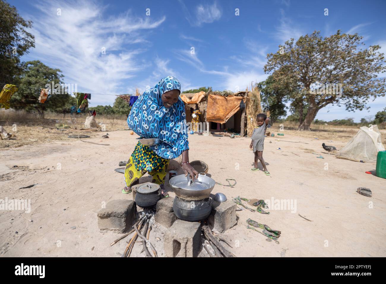 Mother cooking a meal over an open fire in front of the family's home ...