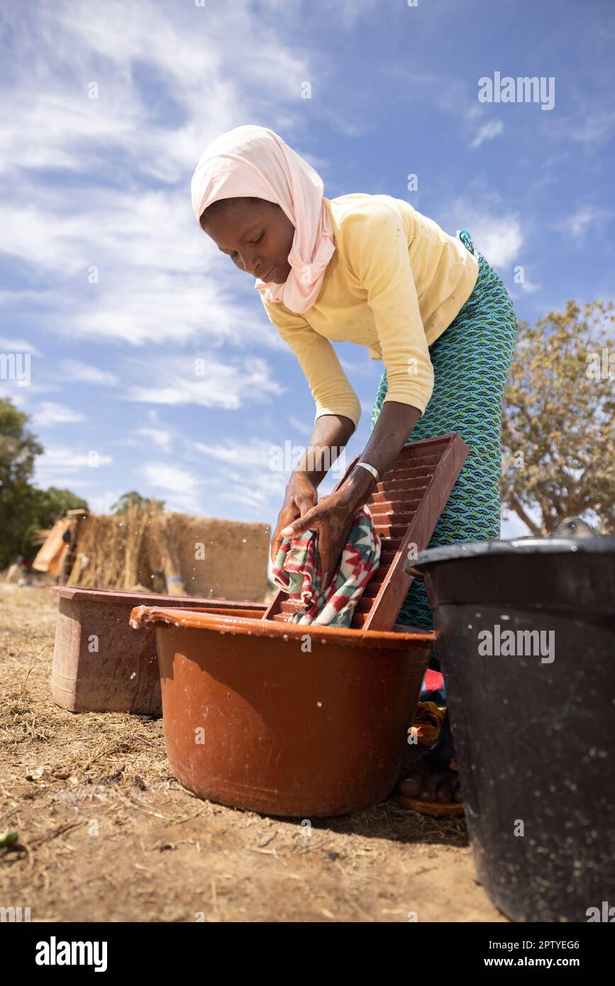 An IDP girl washes clothes with a washing board in Segou Region, Mali ...