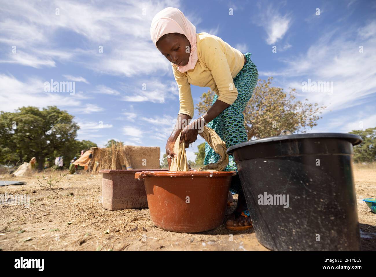 An IDP girl washes clothes with a washing board in Segou Region, Mali ...